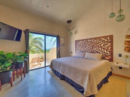 Quarto com cama, televisão na parede, varanda com plantas e painel decorativo.
