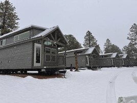 Uma fileira de cabanas com fachada de madeira, varanda e o número 10513 visível.