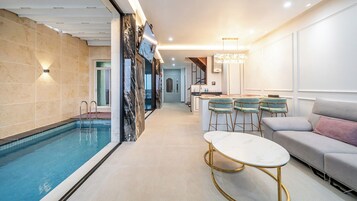 Área interna de piscina moderna, com espaço para sentar e bar.