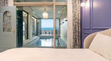 Quarto com cama, vista para uma piscina e varanda com guarda-corpo.