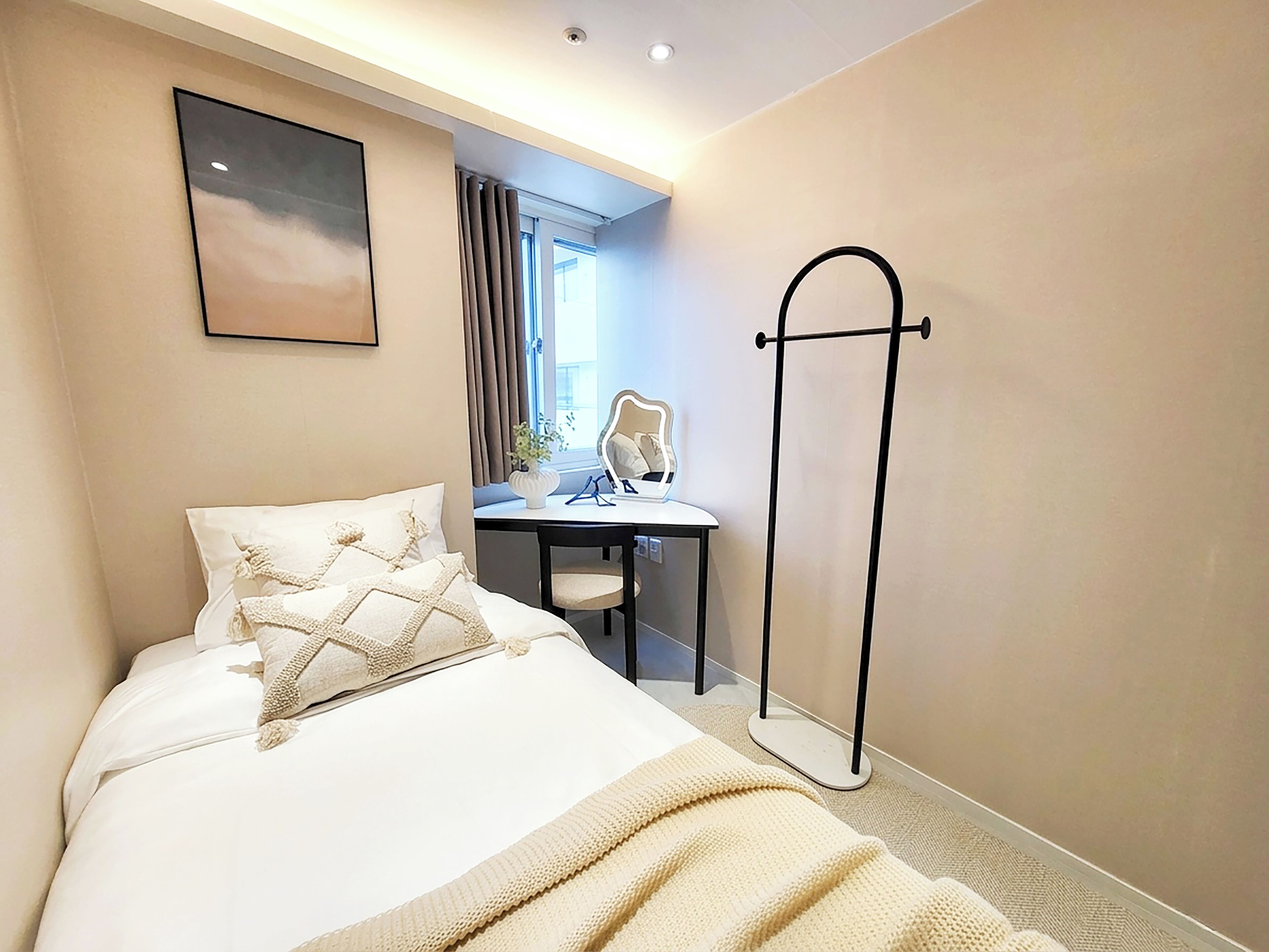 Quarto com cama, escrivaninha, cadeira, espelho e radiador.
