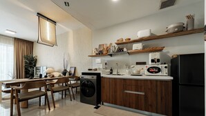 Uma cozinha moderna com armários de madeira, máquina de lavar embutida e frigorífico preto.