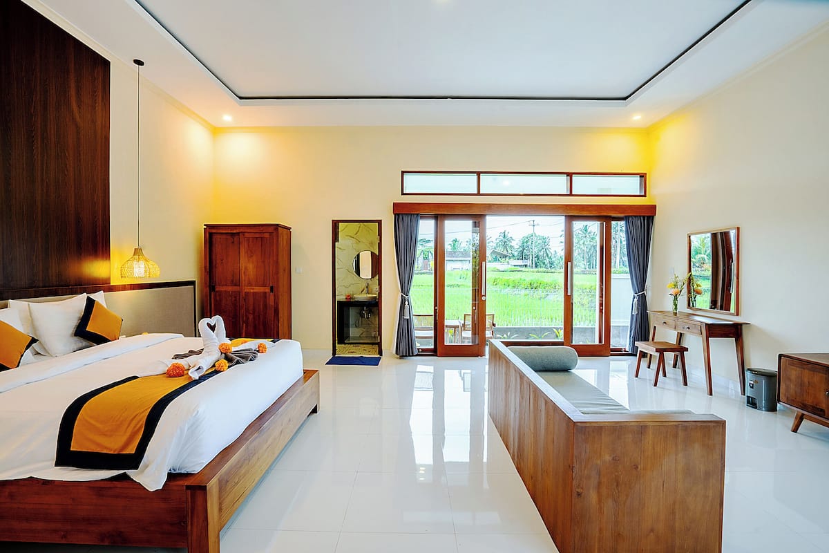 Quarto de hotel com uma cama grande, uma escrivaninha, uma cadeira e vista para o exterior.