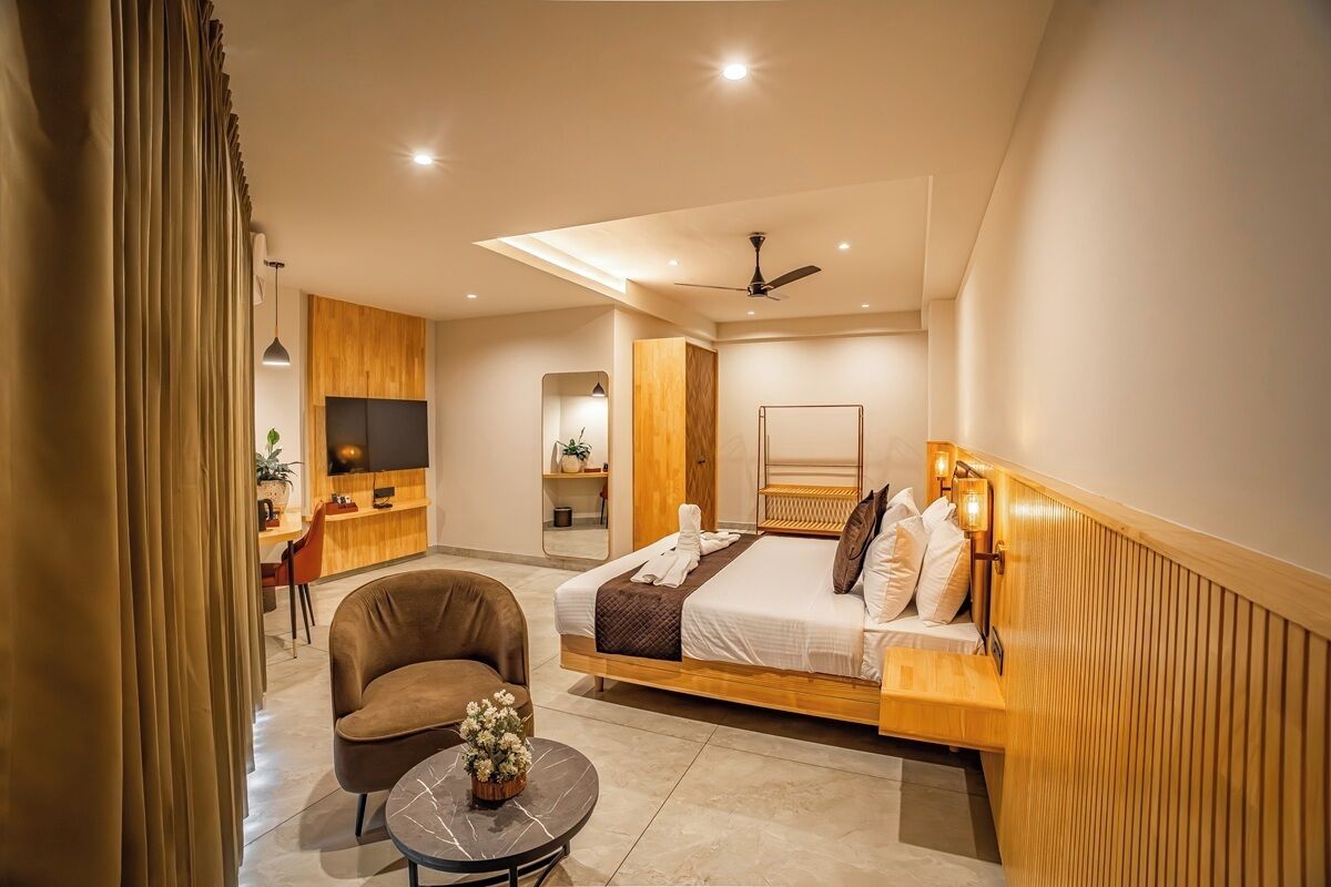 Quarto de hotel moderno com uma cama, área de estar, escrivaninha e televisão.