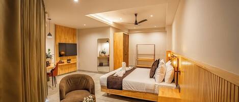 Quarto de hotel moderno com uma cama, área de estar, escrivaninha e televisão.