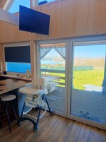 Quarto com uma janela grande, televisão, mudo para troca de fraldas e piso de madeira.