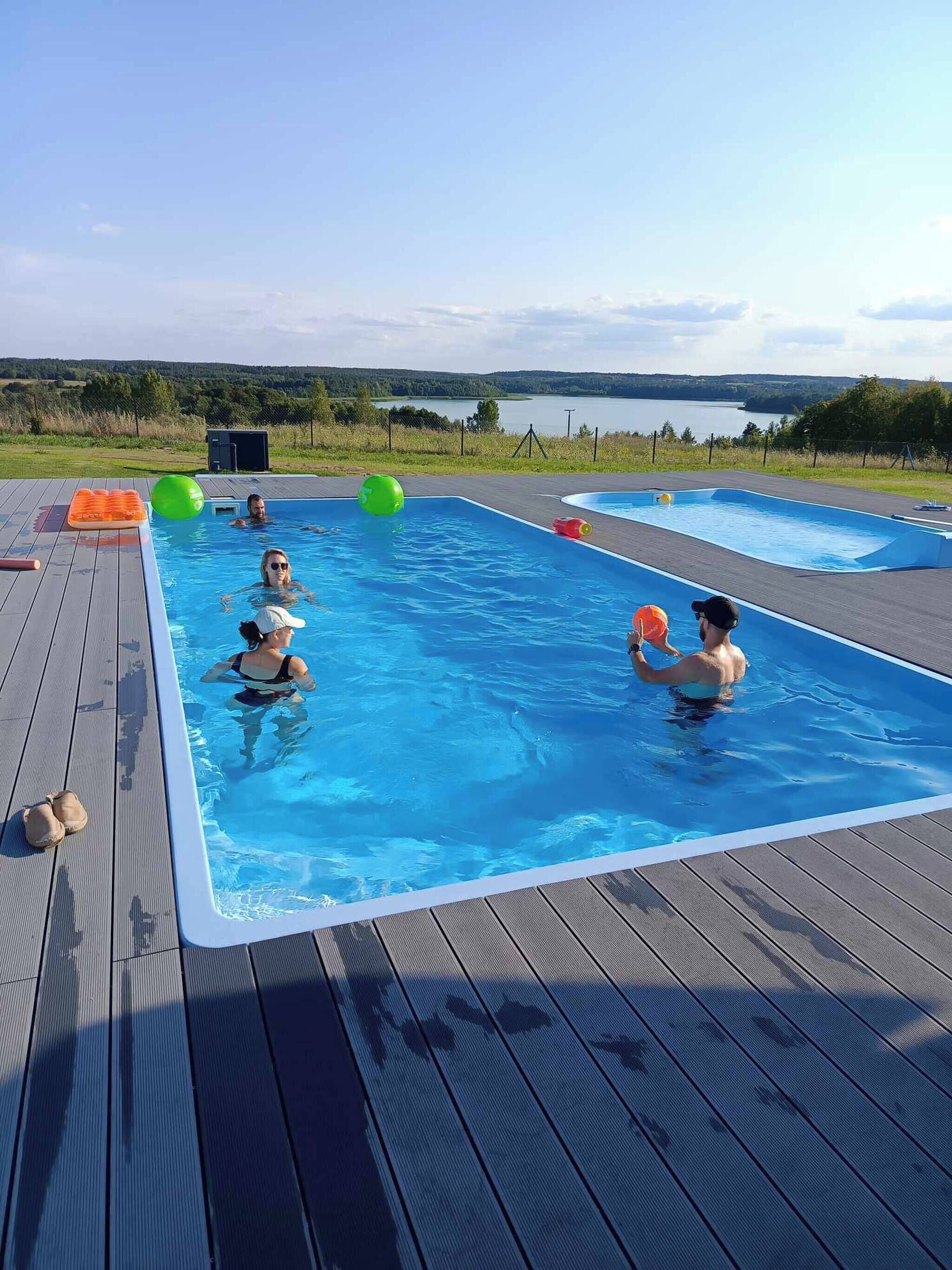 Piscina com deck de madeira, cercada por paisagem natural.