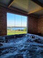 Uma banheira de hidromassagem com vista para um lago e interior de madeira.