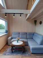 Uma sala de estar moderna com um sofá seccional, uma mesa de centro de madeira e iluminação pendente.
