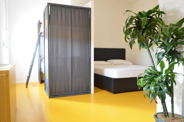 Quarto com cama, uma planta e uma porta de correr.