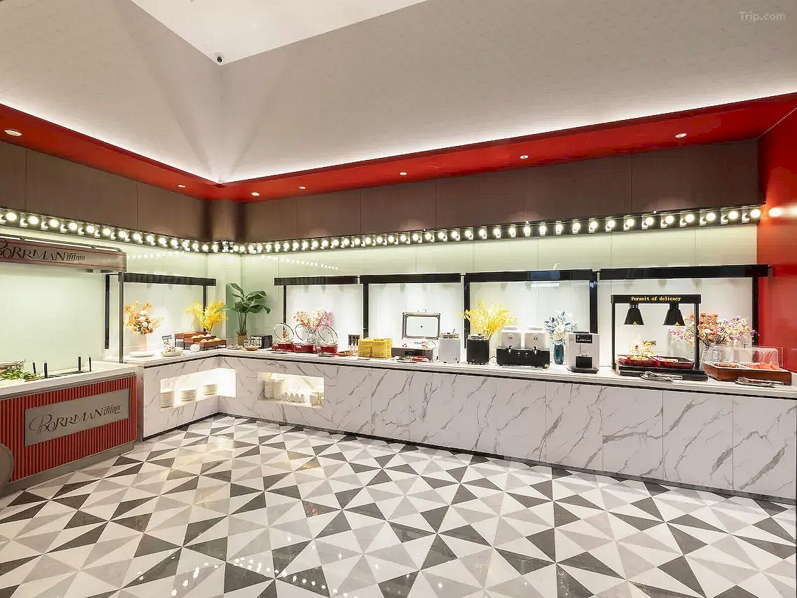 Um hall de hotel moderno com piso de mármore, balcão de recepção e uma parede com detalhes em vermelho.