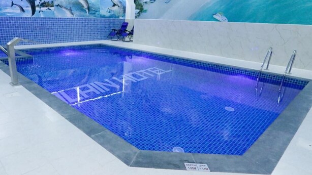 Piscina com borda azulejada, sinal de profundidade e um mural de golfinhos.