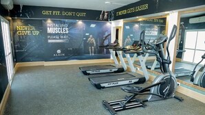 Uma academia com esteiras, elípticos e cartazes motivacionais nas paredes.
