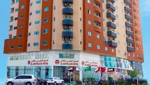 Um hotel com vários andares, varandas, um átrio central e sinalização para o Al Ain Palace Hotel.