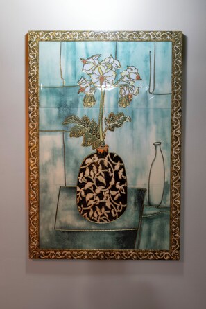 Uma obra de arte emoldurada retratando um vaso com flores e folhas.