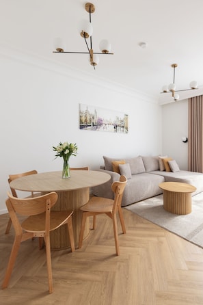 Uma área de refeições moderna com uma mesa de madeira redonda, cadeiras e um vaso de flores.