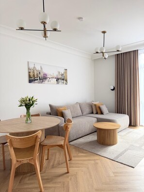 Uma sala de estar moderna com um sofá, uma mesa de jantar com cadeiras, uma mesa de centro e um quadro na parede.
