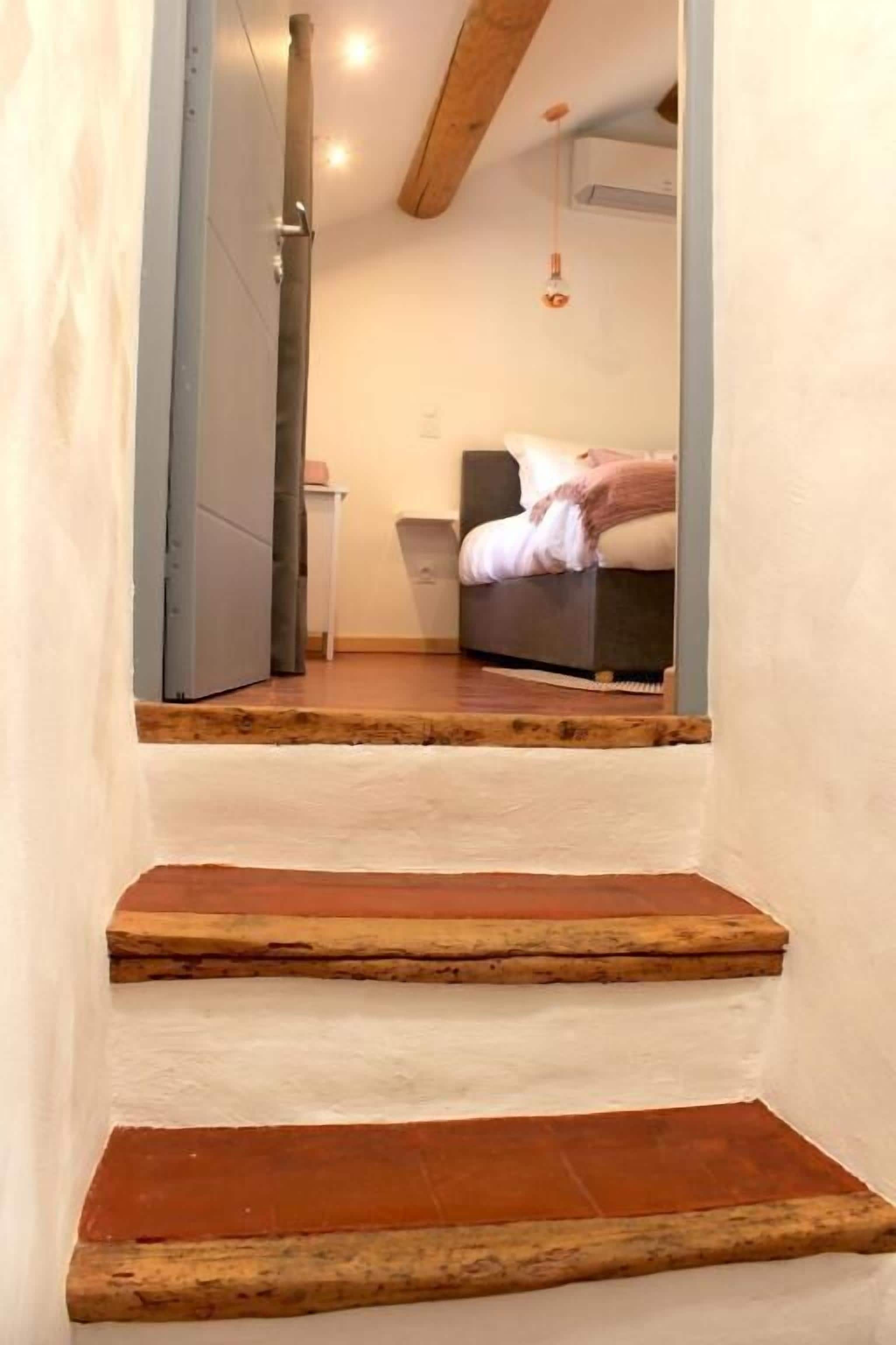 Quarto com cama, mesa de cabeceira e janela.
