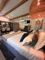 Quarto moderno com uma cama grande, área de estar e televisão.