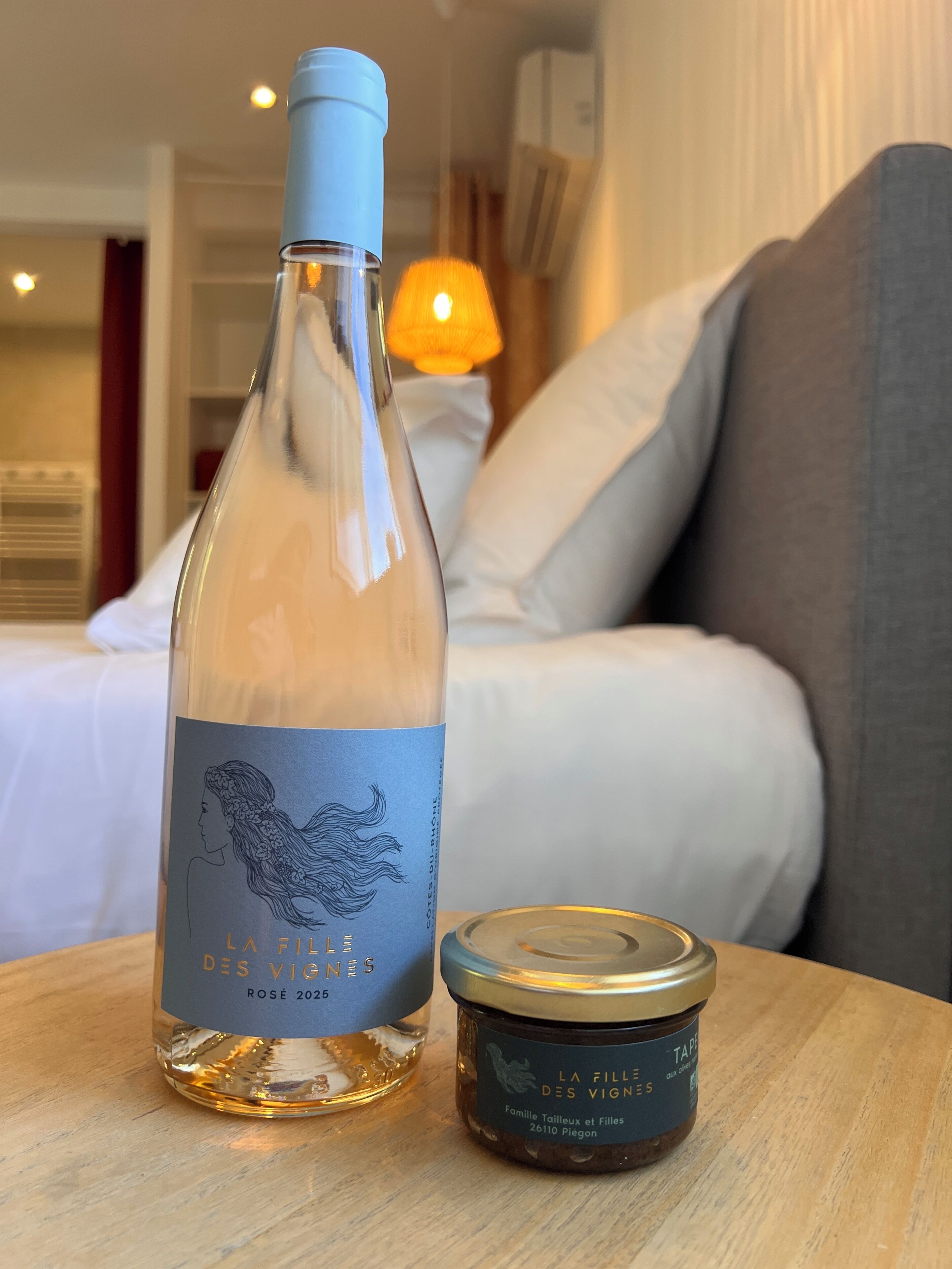 Uma garrafa de vinho e um pote de azeite em cima de uma mesa de madeira num quarto de hotel.