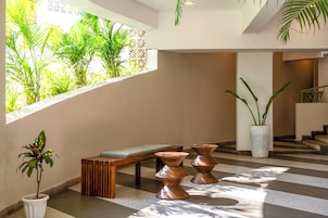 Um interior moderno com um banco, dois cachepots de cobre e uma janela ampla com vista para o verde.