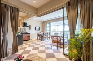 Uma sala ampla com piso xadrez, um conjunto de jantar e uma varanda com cortinas.