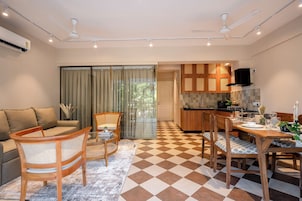 Uma sala de estar moderna com sofá, cadeiras, mesa de jantar e área de cozinha com armários e fogão.