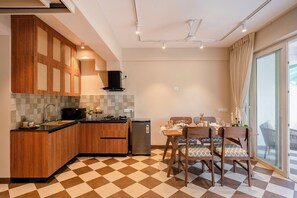 Uma cozinha com armários de madeira, geladeira, micro-ondas e um espaço de jantar com mesa e cadeiras.