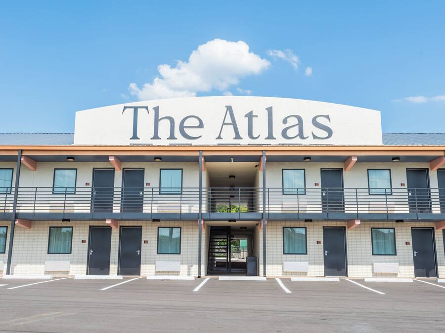 Um edifício de dois andares com uma placa que diz 'The Atlas' acima da entrada.