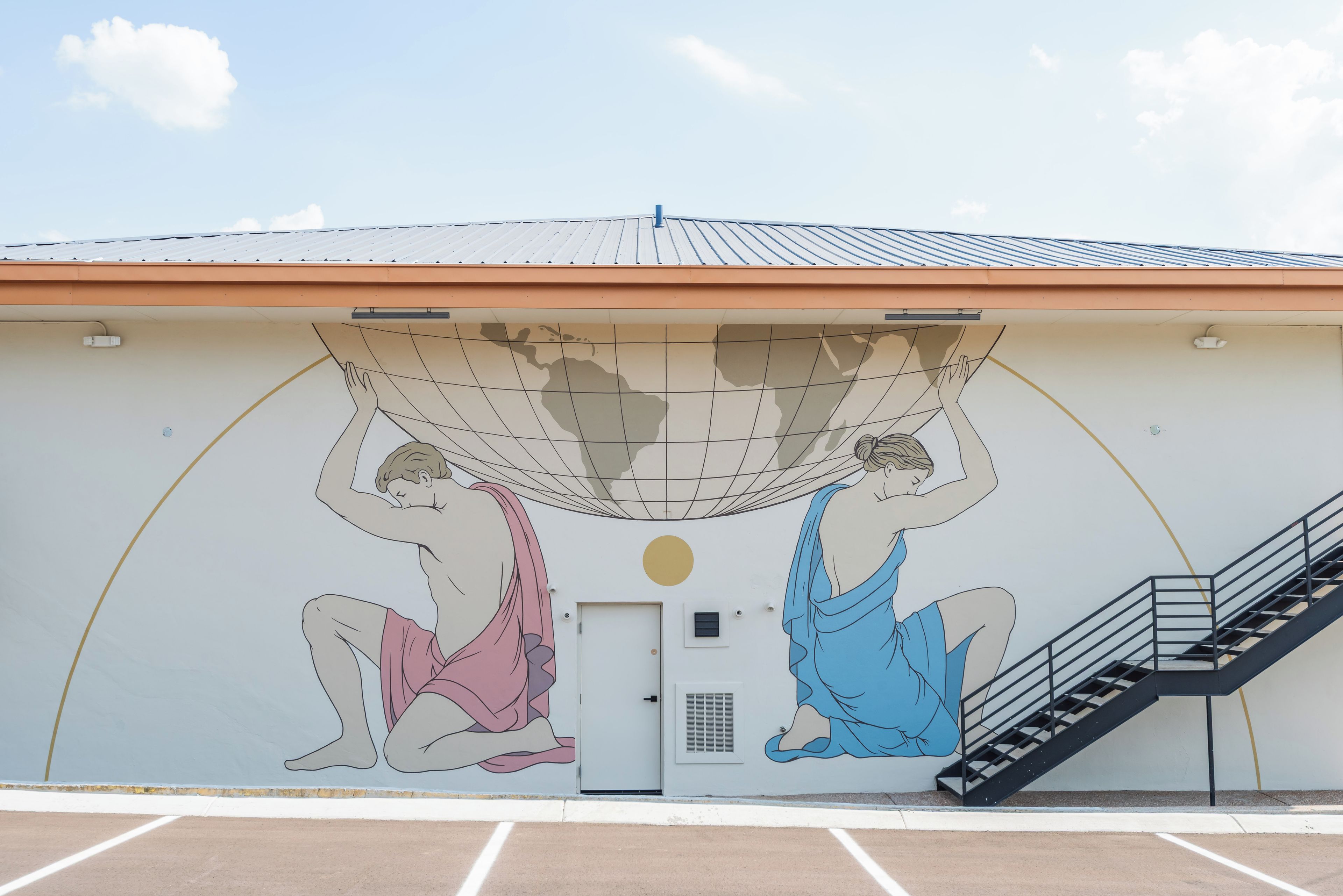 Edifício com um mural de duas figuras, uma porta e uma escadaria.