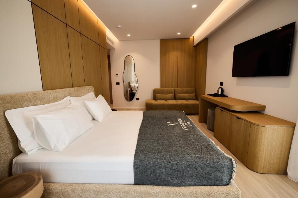 Quarto de hotel moderno com uma cama grande, uma mesa, uma televisão e um espelho.