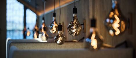Vários pendentes com superfície refletora suspensos no teto de um espaço interno bem iluminado.