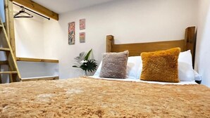 Quarto com cabeceira de madeira, colcha marrom fofa e escada de madeira.