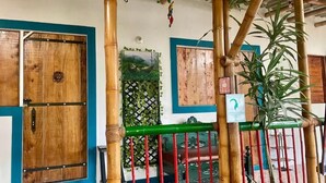 Uma porta de madeira com uma trava de metal, cerca de bambu e uma planta verde.