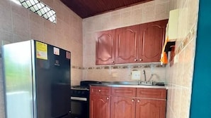 Cozinha com armários de madeira, geladeira preta e piso revestido com azulejos.
