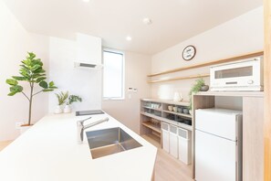 Uma cozinha moderna com uma ilha central, eletrodomésticos embutidos e uma planta em vaso.