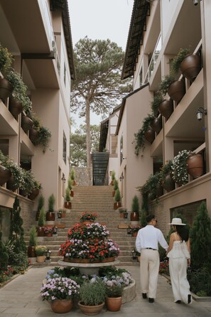 Um edifício com várias varandas, vasos de plantas e uma escadaria central que leva a um andar superior.