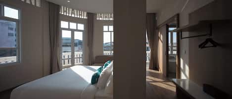 Quarto de hotel com cama grande, mesa de cabeceira, guarda-roupa e vista para a cidade.