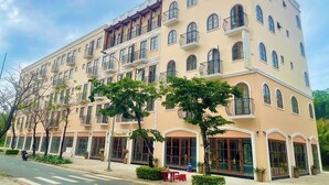 Um hotel com vários andares, varandas, janelas amplas e uma placa com a inscrição 'Huang Hotel'.