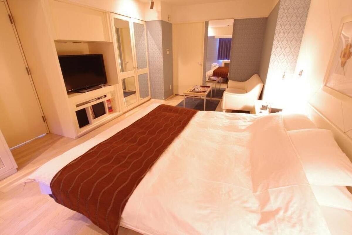 Quarto de hotel com cama, televisão, escrivaninha e cadeira.