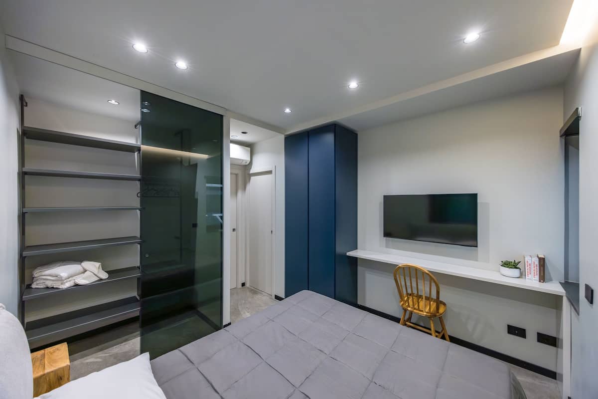 Quarto com cama, televisão, cadeira e guarda-roupa.