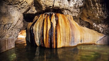 Grande formação rochosa em uma caverna, com água na base.