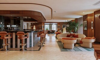 Um saguão de hotel moderno com um bar curvo, área de estar e vista para o exterior.