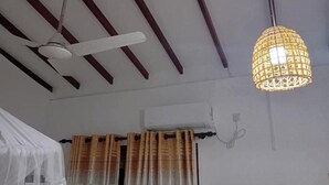 Quarto com ventilador de teto, luminária pendente e janela com cortinas.