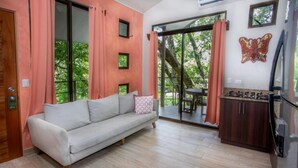 Quarto com sofá, mesa de jantar e cozinha.