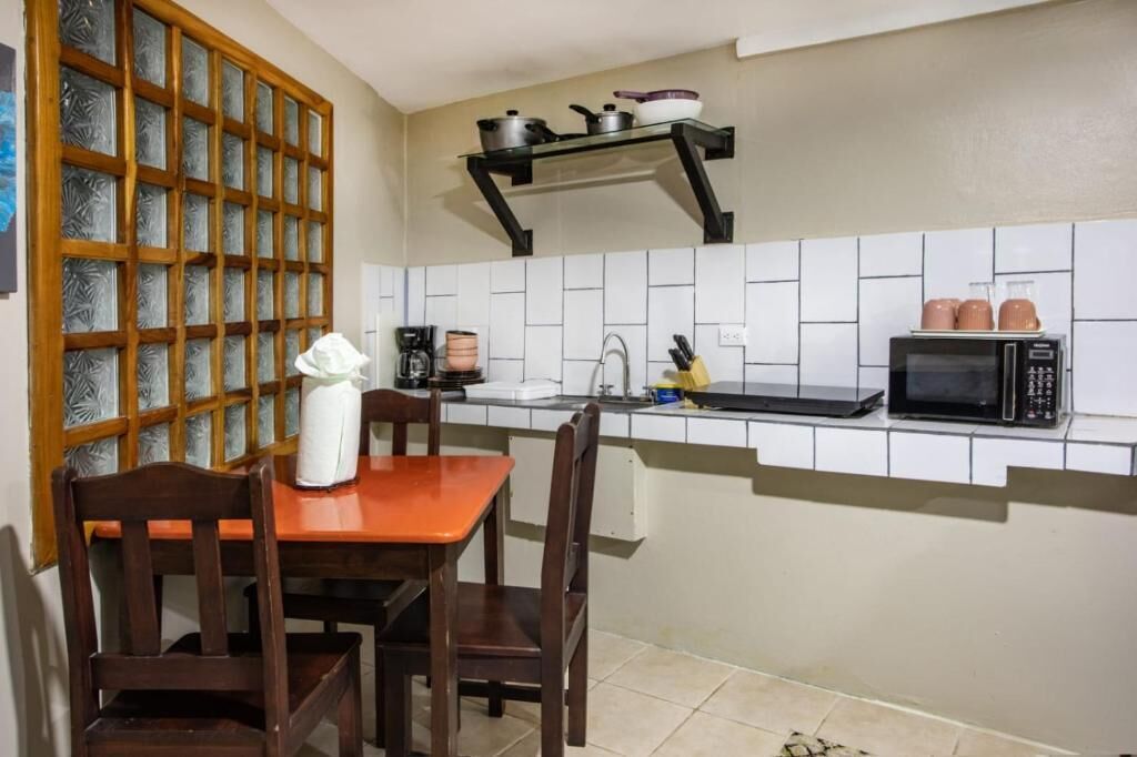 Cozinha compacta com mesa de jantar, cadeiras, micro-ondas e cafeteira.