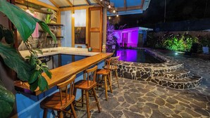 Uma área de bar com piscina, degraus de pedra e balcão de madeira.