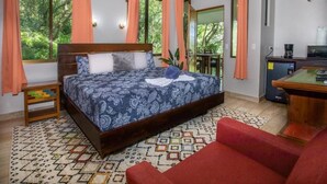 Quarto com cama, escrivaninha, cadeira e vista para o verde lá fora.