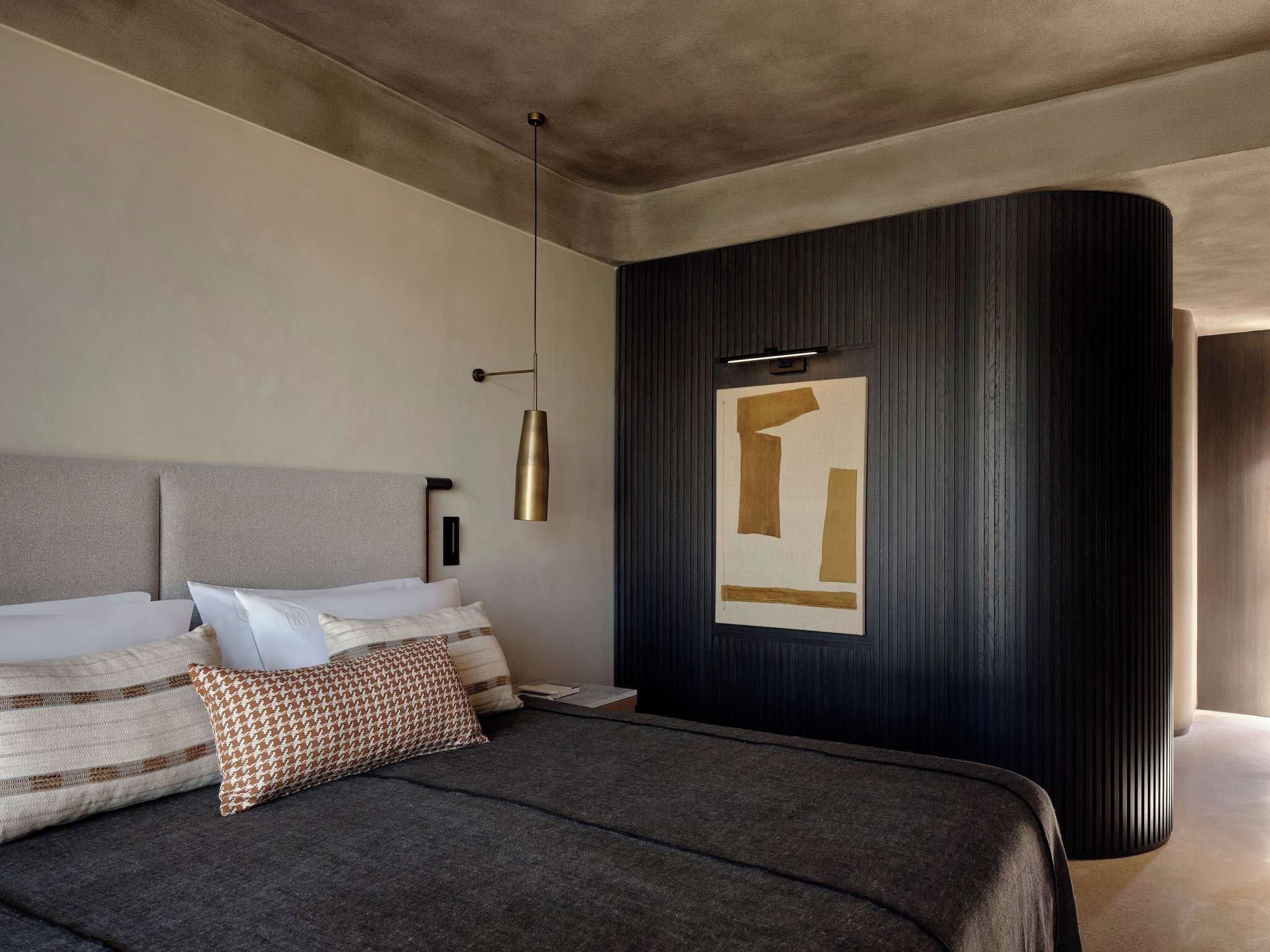 Quarto moderno com cama grande, obra de arte na parede e design minimalista.