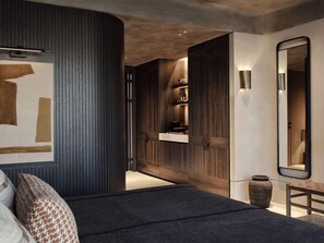 Quarto moderno com cama de cor escura, um espelho grande e um guarda-roupa de madeira.